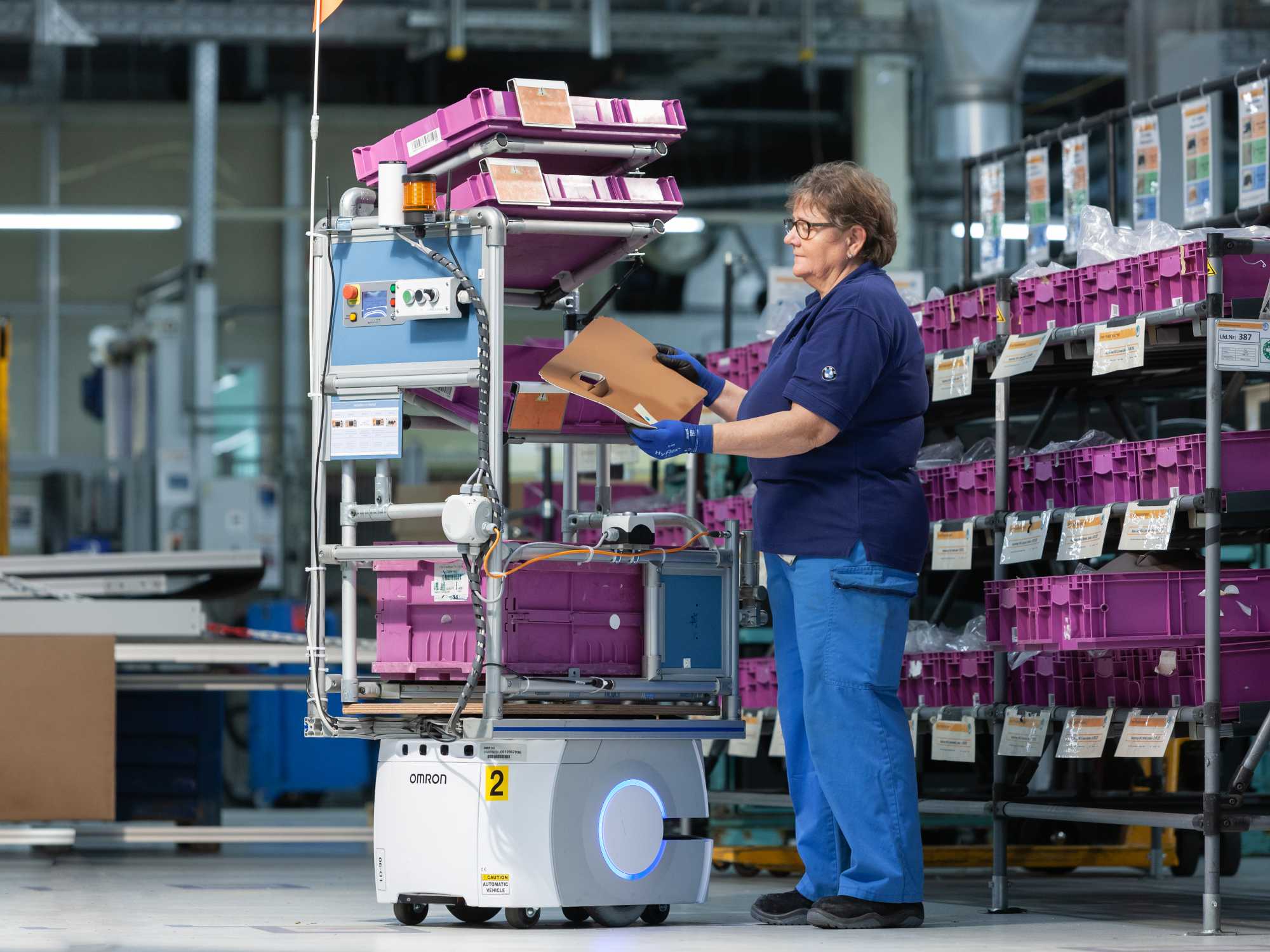 Eine Mitarbeiterin bestückt das autonome Transportsystem, das ohne ...
